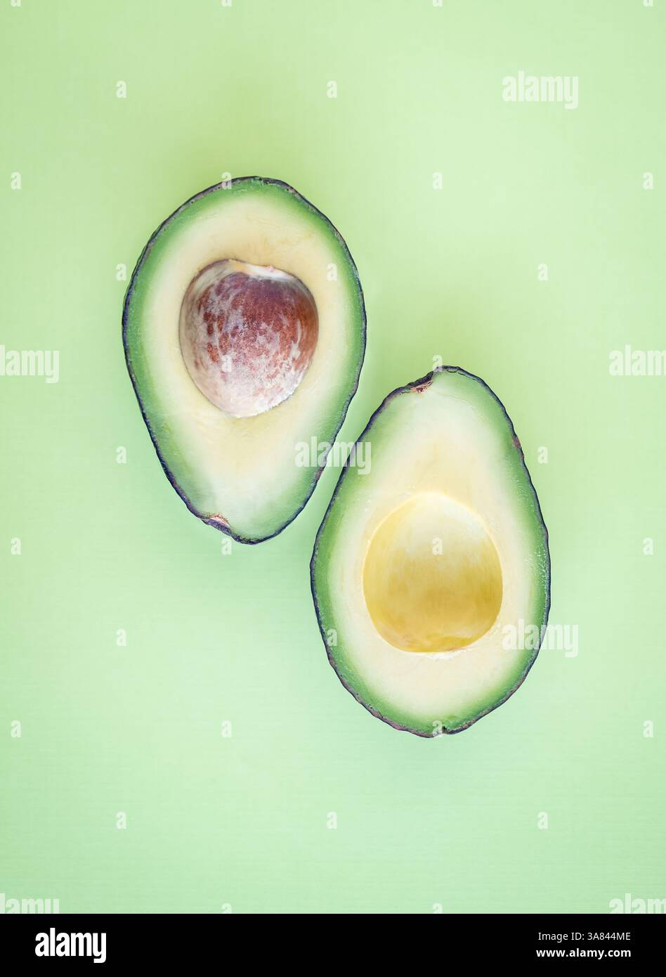 Top view of single avocado cut in half on solid green background Stock ...