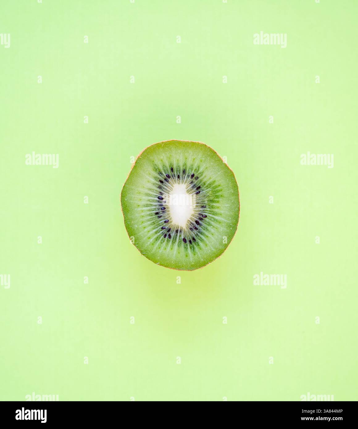 Isolated cross section of single kiwi fruit on solid green background ...