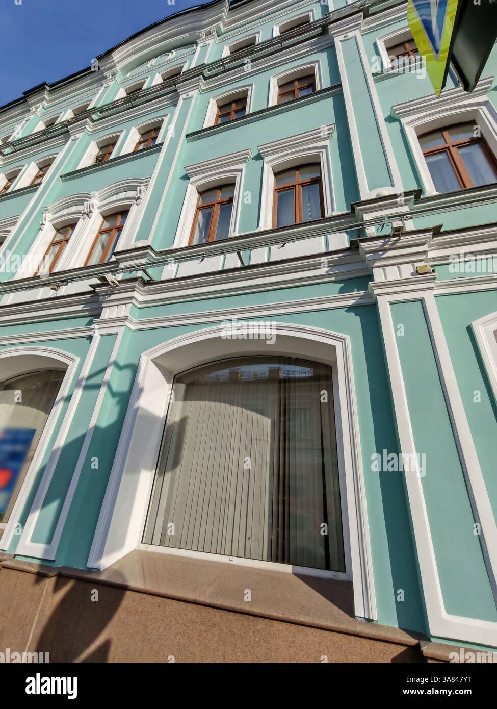A mint-green building facade with large arched and rectangular windows ...