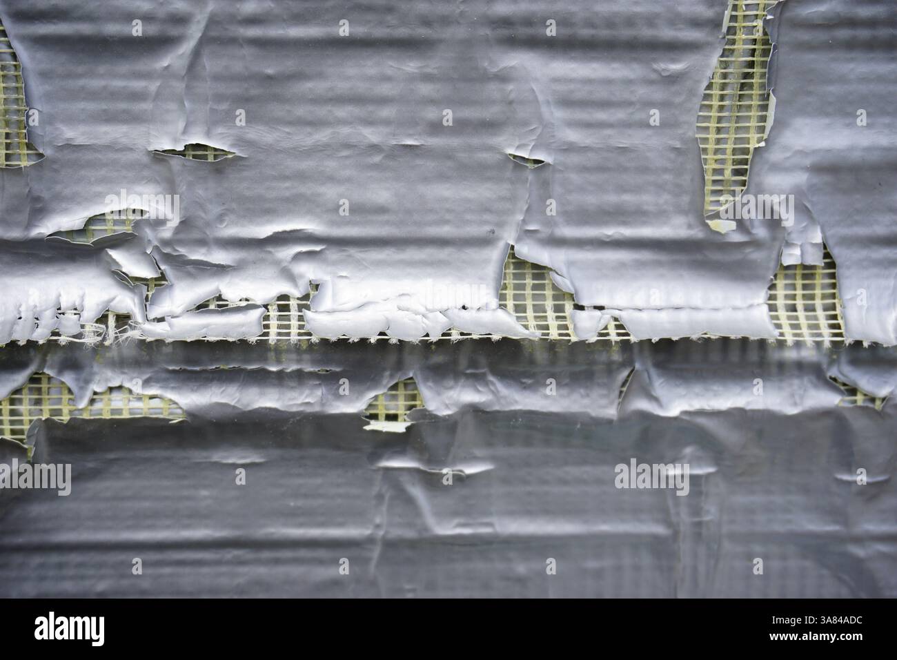 A damaged roof with torn shingles and exposed insulation, indicating ...
