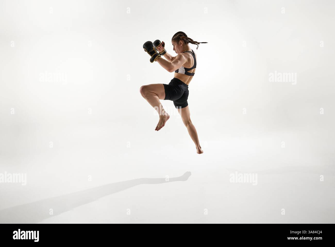 Focused athlete in black boxing gear performing high jump for attack ...