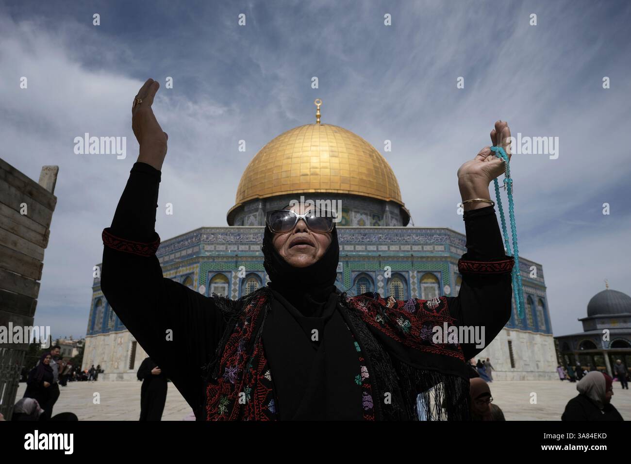 A woman prays next to the Dome of the Rock Mosque in the Al-Aqsa Mosque ...