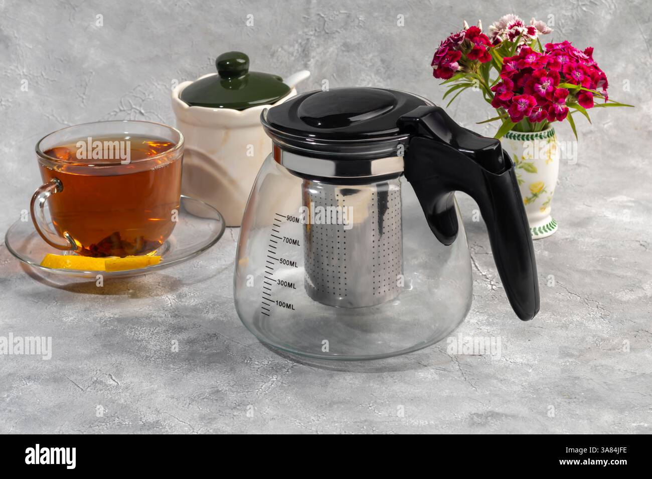 Glass teapot with metal strainer inside. Kitchen utensils on gray ...