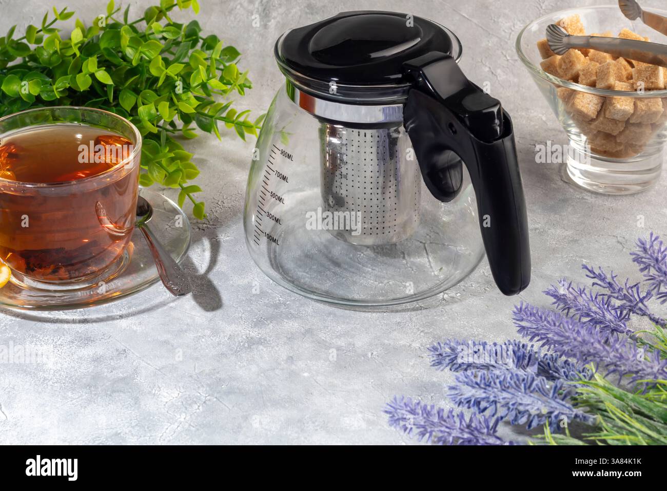 Glass teapot with metal strainer inside. Kitchen utensils on gray ...