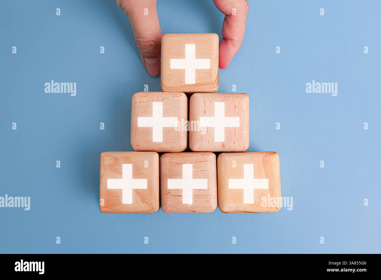 A hand places the top wooden block on a pyramid of six blocks, each ...