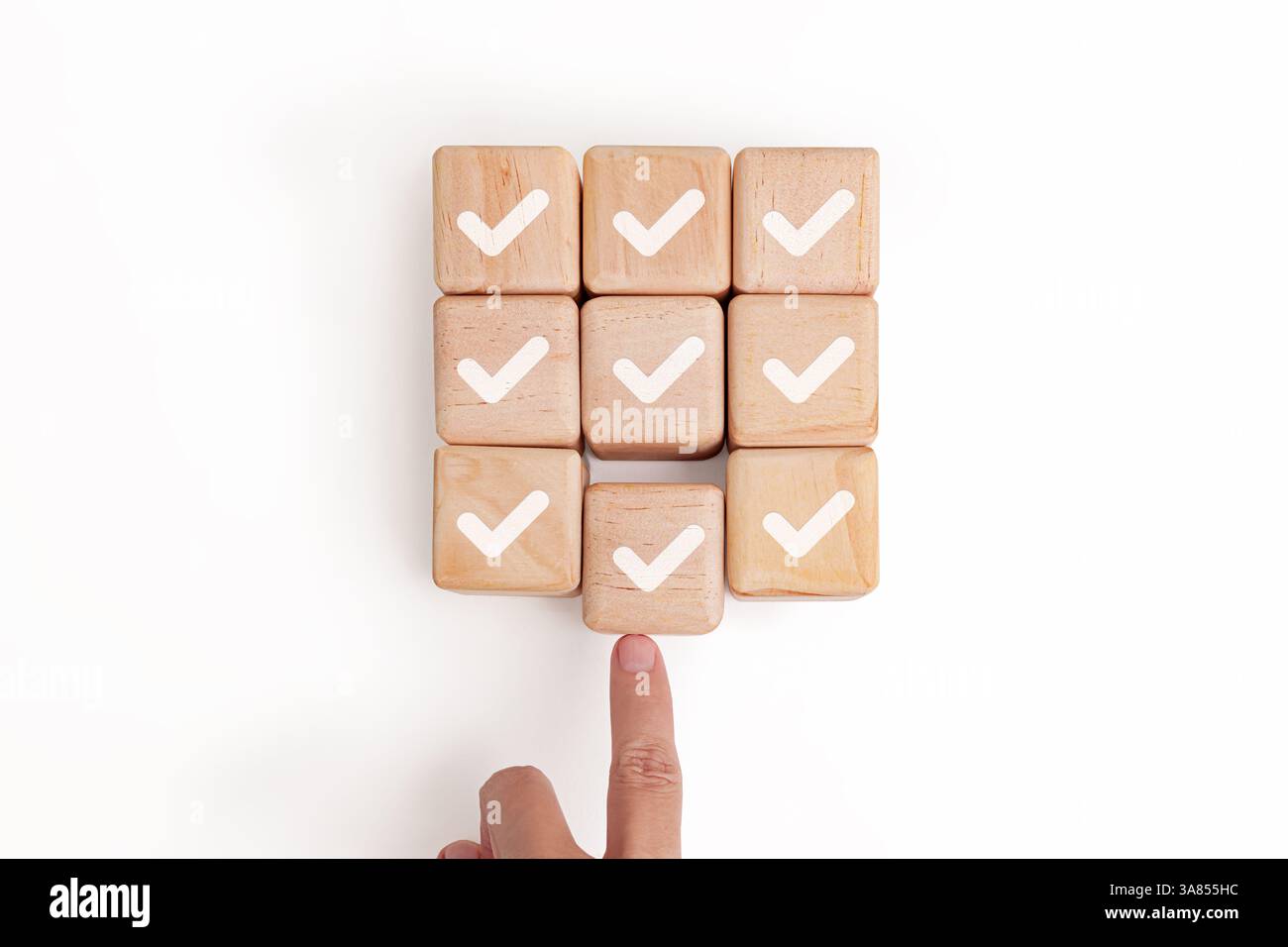 A person points at a wooden block in a 3x3 grid of natural wood cubes ...
