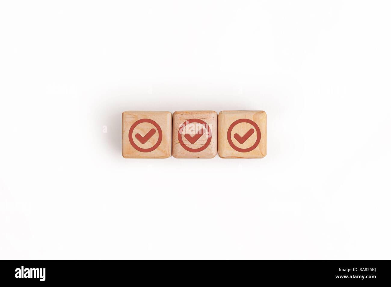 Three wooden blocks with red checkmarks are aligned in a row on a white ...