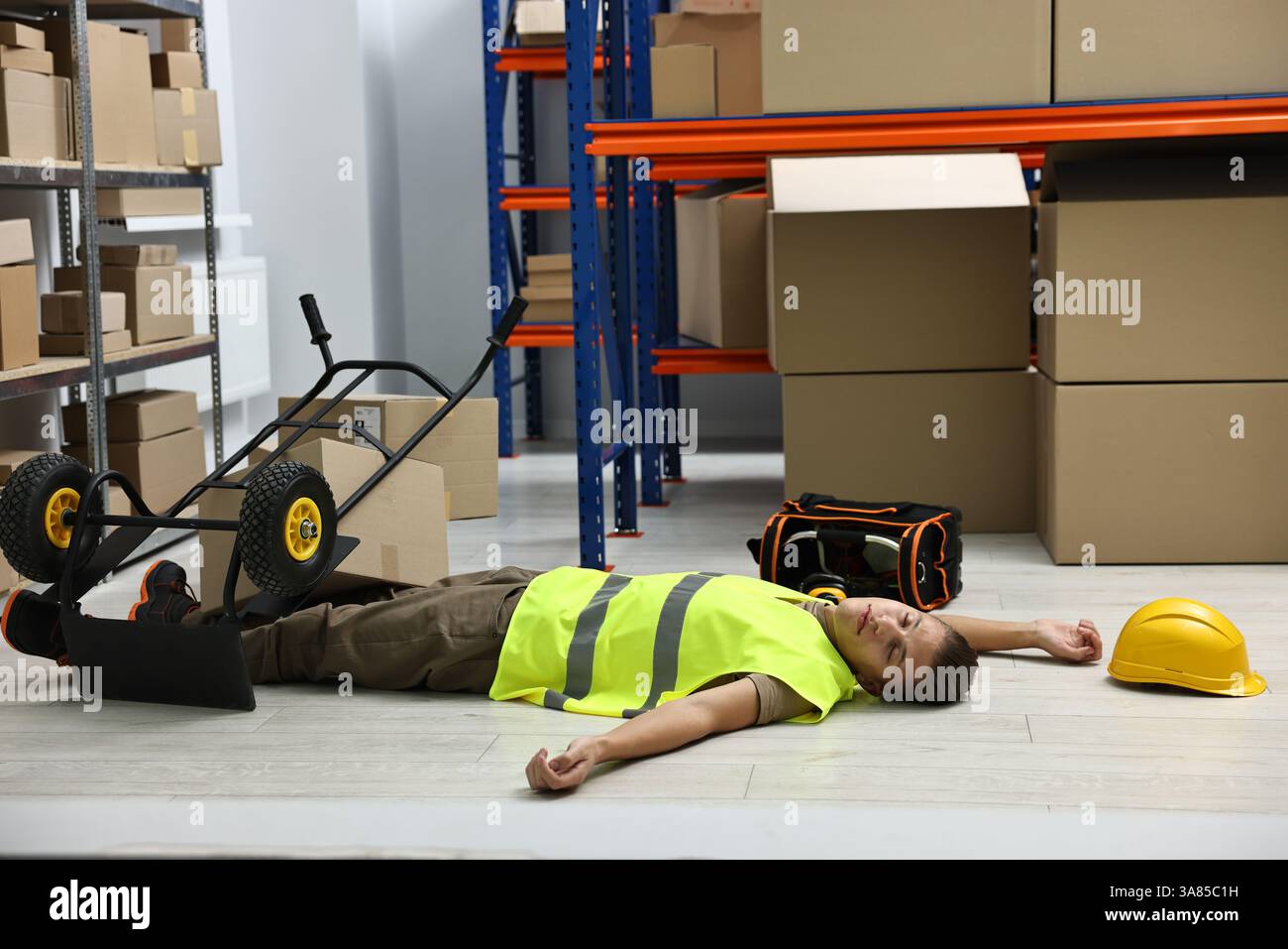 Accident at work. Unconscious man and overturned hand truck on floor in ...