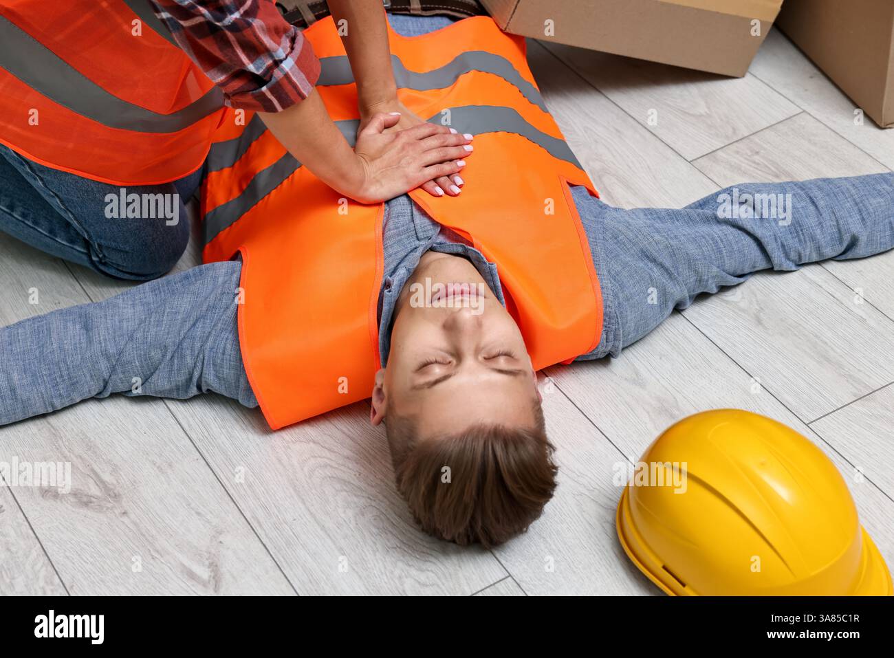 Accident at work. Woman performing CPR on her unconscious colleague in ...