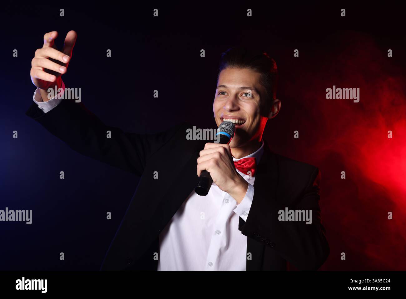 Talented singer performing on dark background with color lights and ...
