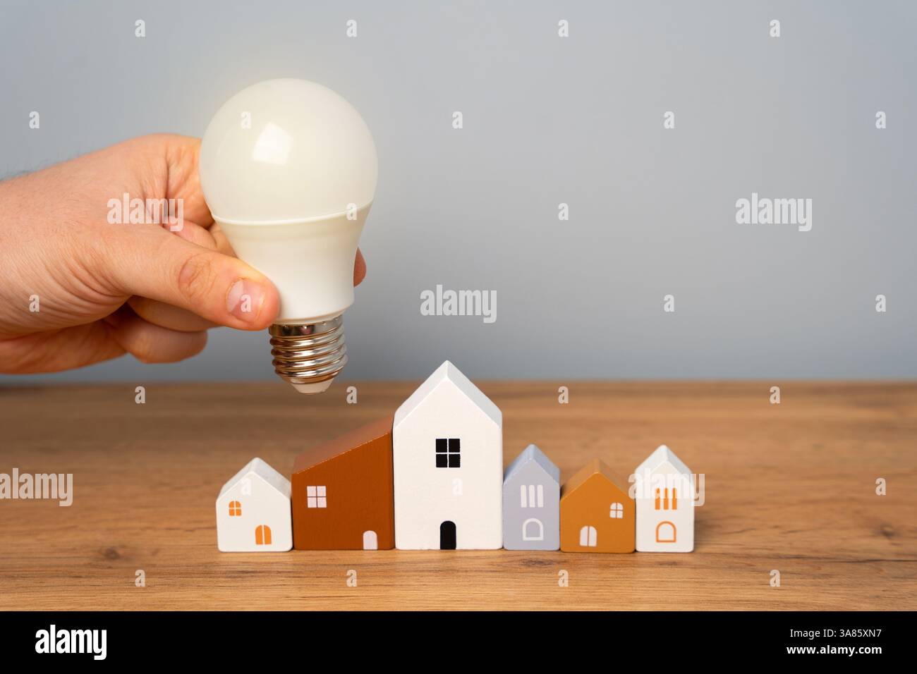Hand holding light bulb to residential buildings. Concept of power ...