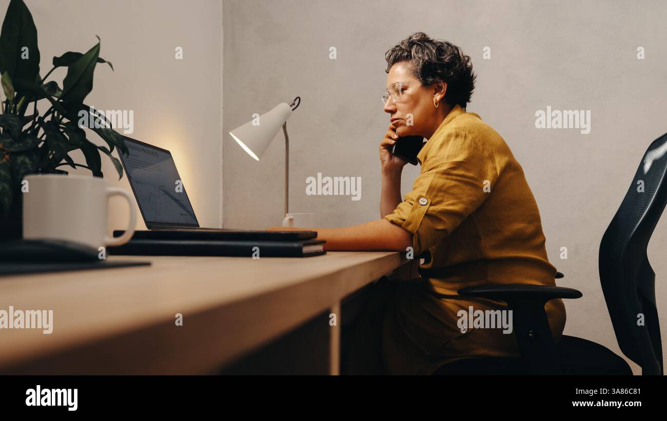 A professional mature woman engaged in a phone call while working at ...