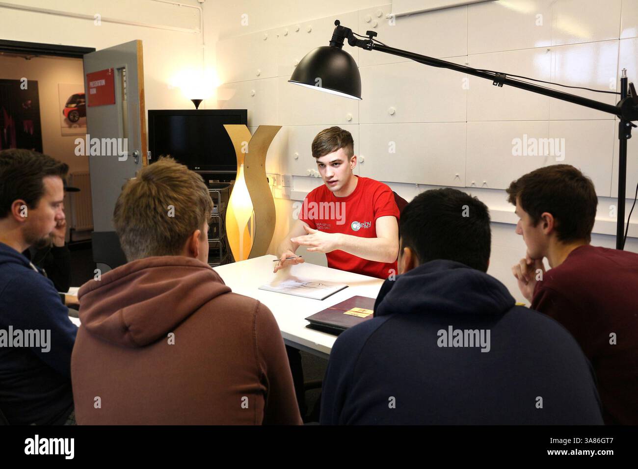 young design tutor demonstrates car design sketching to a small group ...