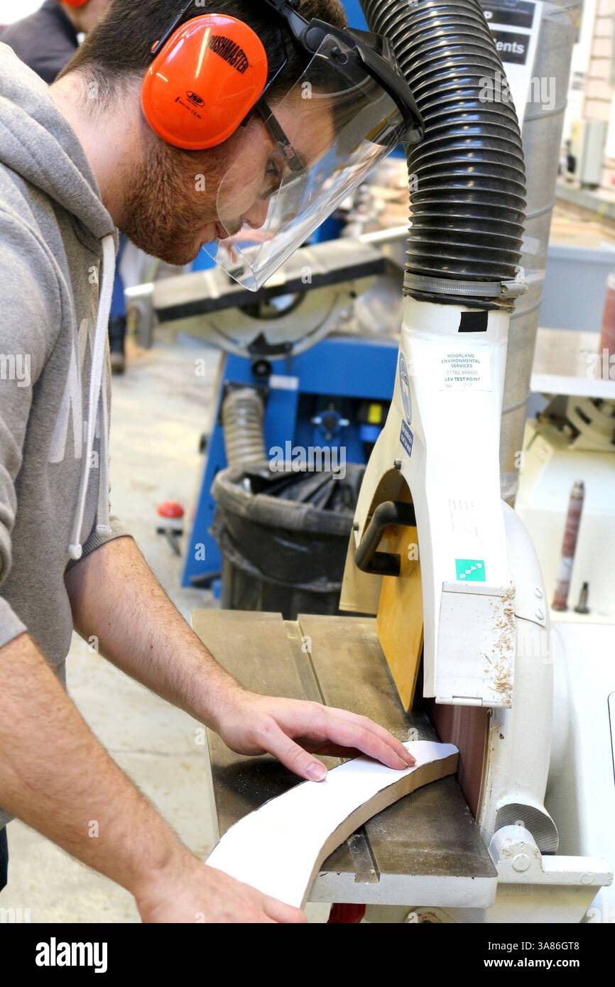 design student man with beard PPE protection using disc sander in wood ...