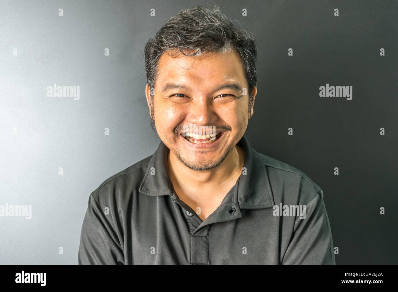 Asia man 40s in black polo shirt have a laughing smile gesture with ...