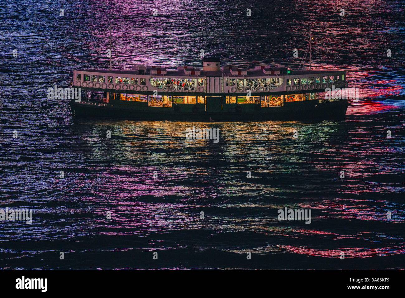 The Star Ferry at night with the reflections of the buildings in the ...
