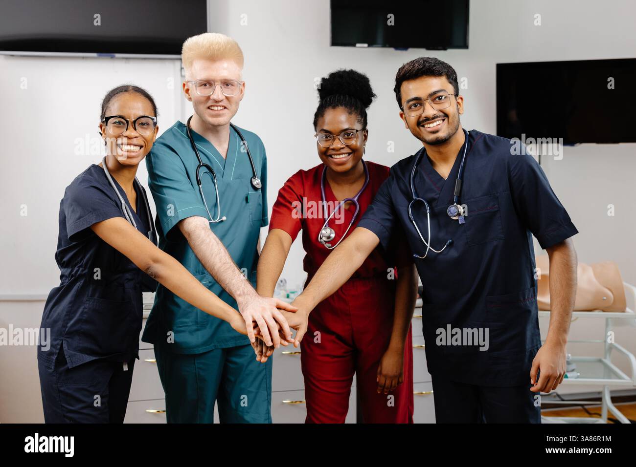 Four healthcare professionals wearing scrubs and stethoscopes are ...