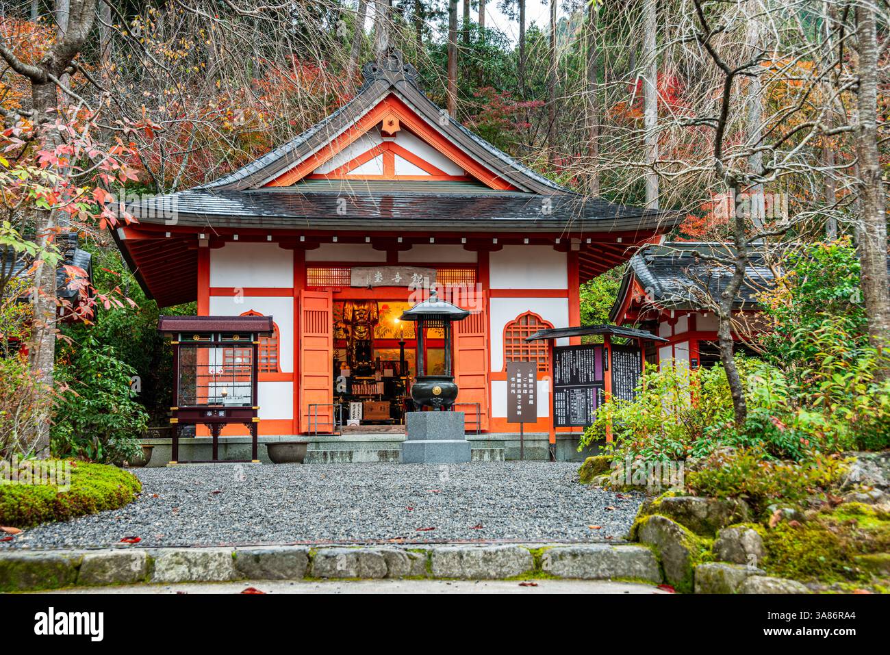 A vibrant red shrine surrounded by greenery and autumn colors, located ...
