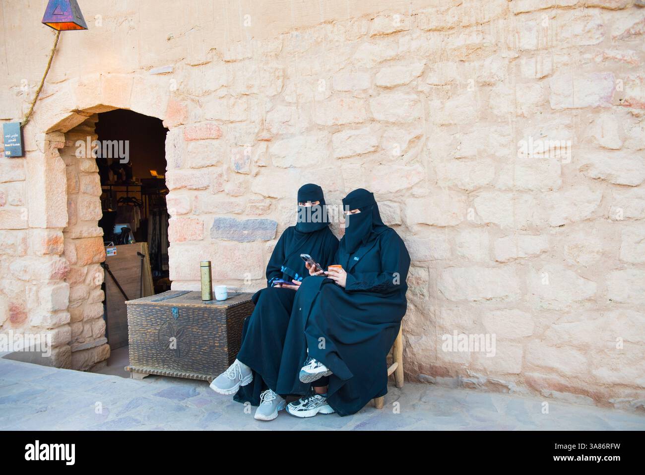 Two young women sitting in front of the shop where they work, old town ...
