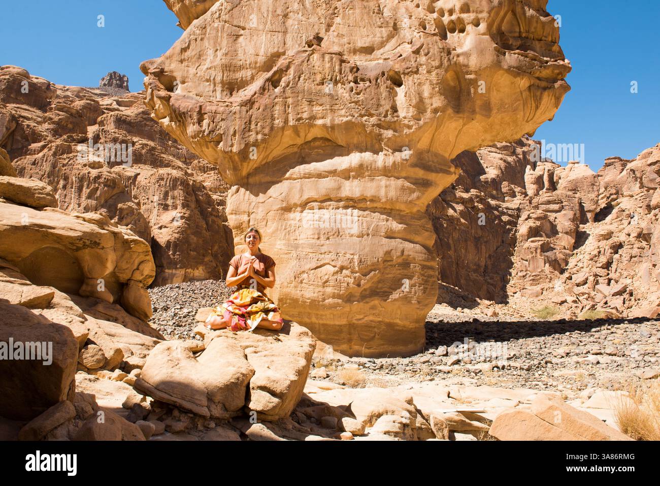 Woman practising yoga poses among sandstone rock formation in the ...