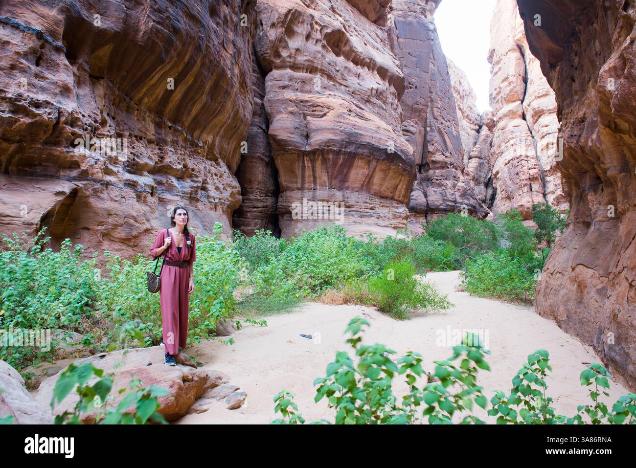 Woman walking at the bottom of a canyon with sandstone walls in the ...