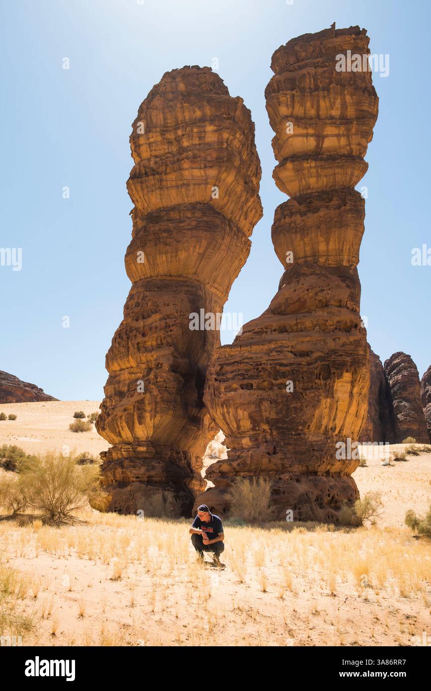 Man squatting beside extraordinary sandstone rock structure called ...