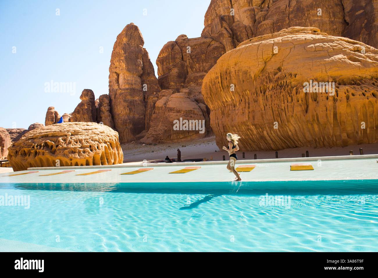 Woman running on edge of swimming pool of Our Habitas AlUla, resort in ...