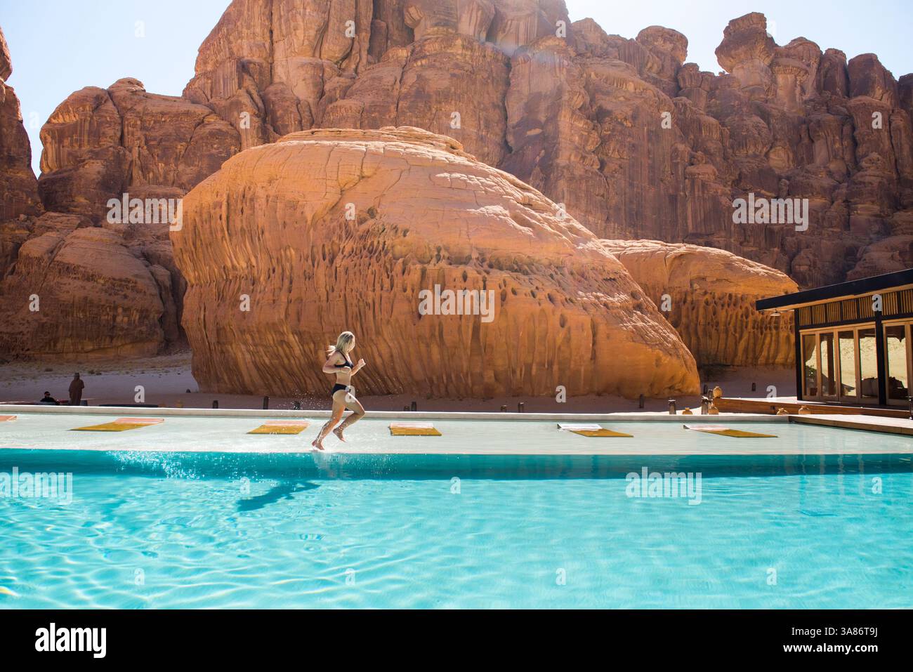 Woman running on edge of swimming pool of Our Habitas AlUla, resort in ...