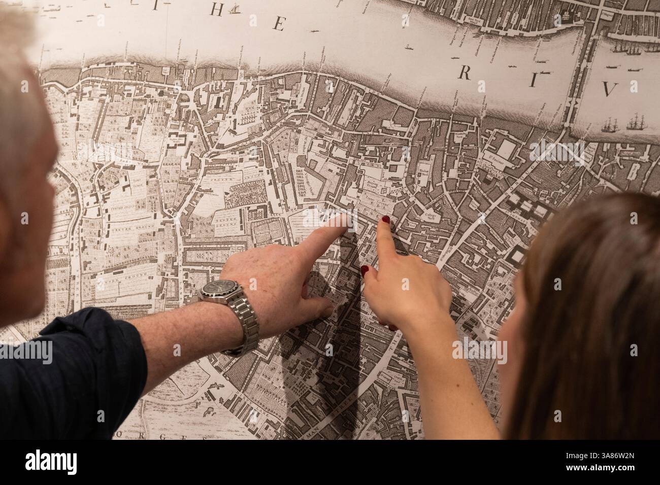 People examine a historical map of London Bankside, focusing on the ...