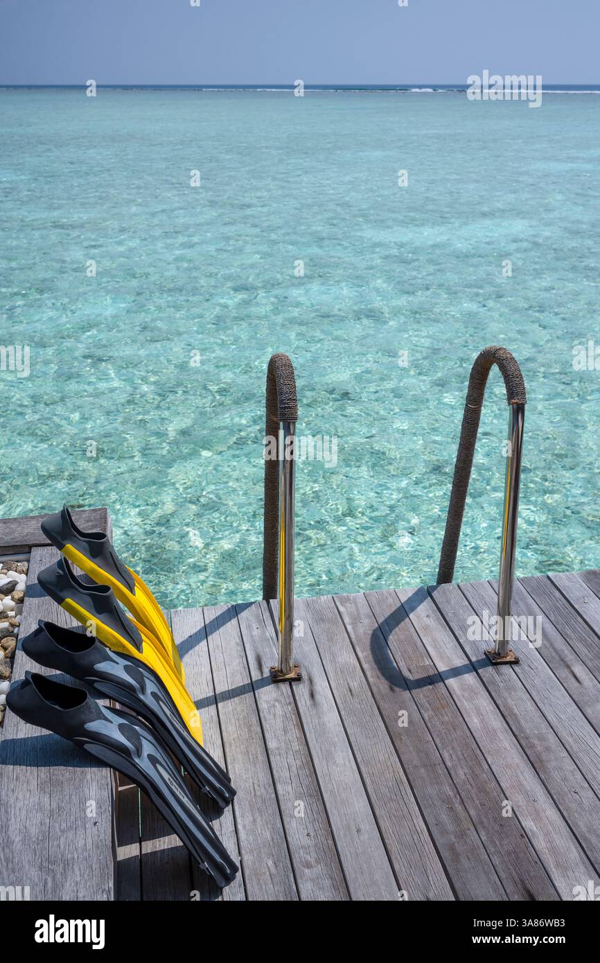 Fins (flippers) drying on a deck overlooking the crystal clear lagoon ...