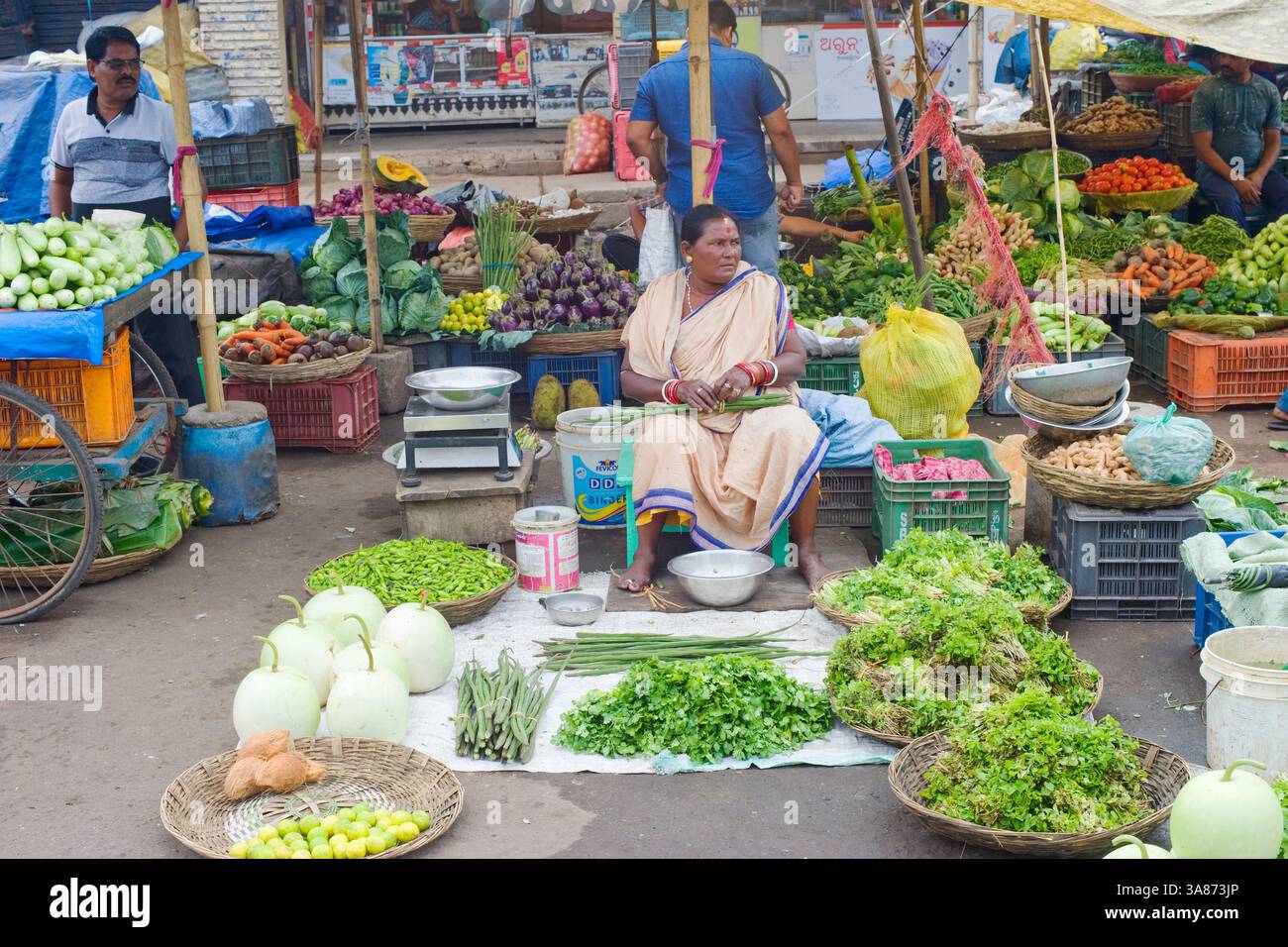 A fruit and vegetable seller and her wares in the centre of Puri near ...