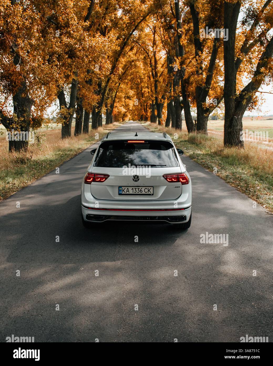 Silver Volkswagen Tiguan on a countryside road on autumn day. Vertical ...