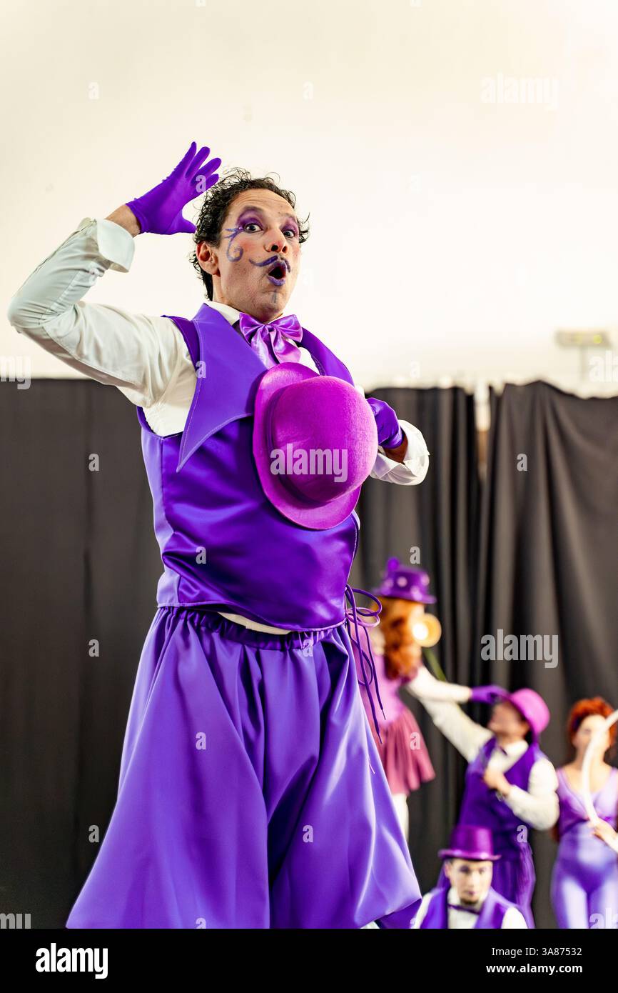Comedian wearing purple suit and bowler hat performing a funny sketch ...