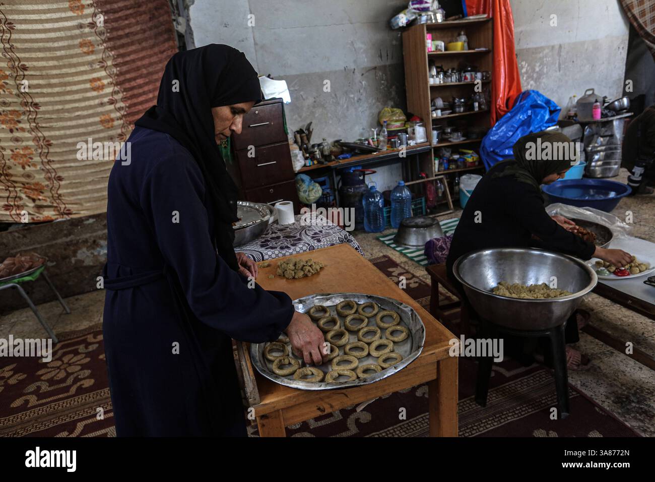 A Palestinian family prepares traditional cookies in preparation for ...