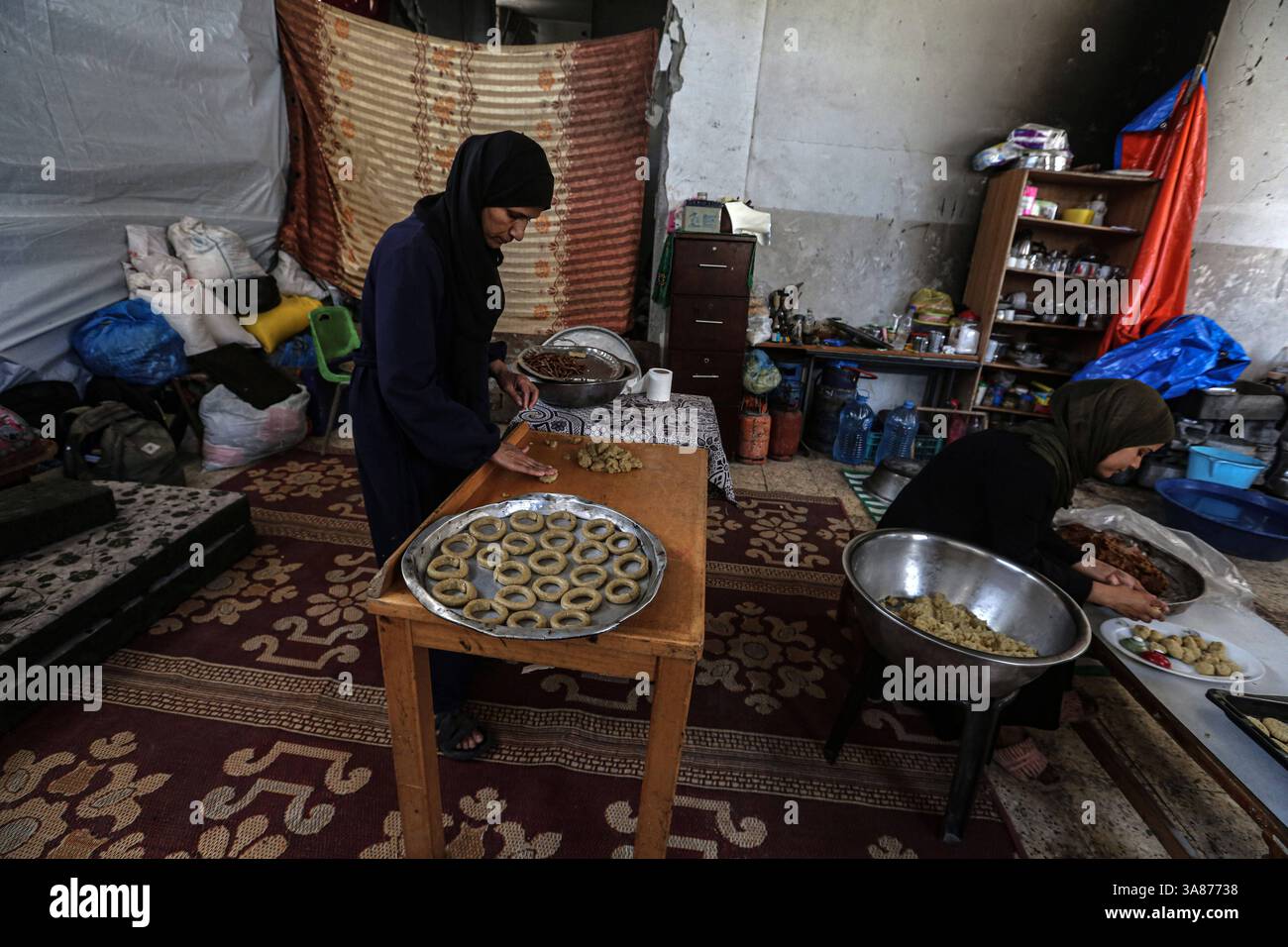 A Palestinian family prepares traditional cookies in preparation for ...