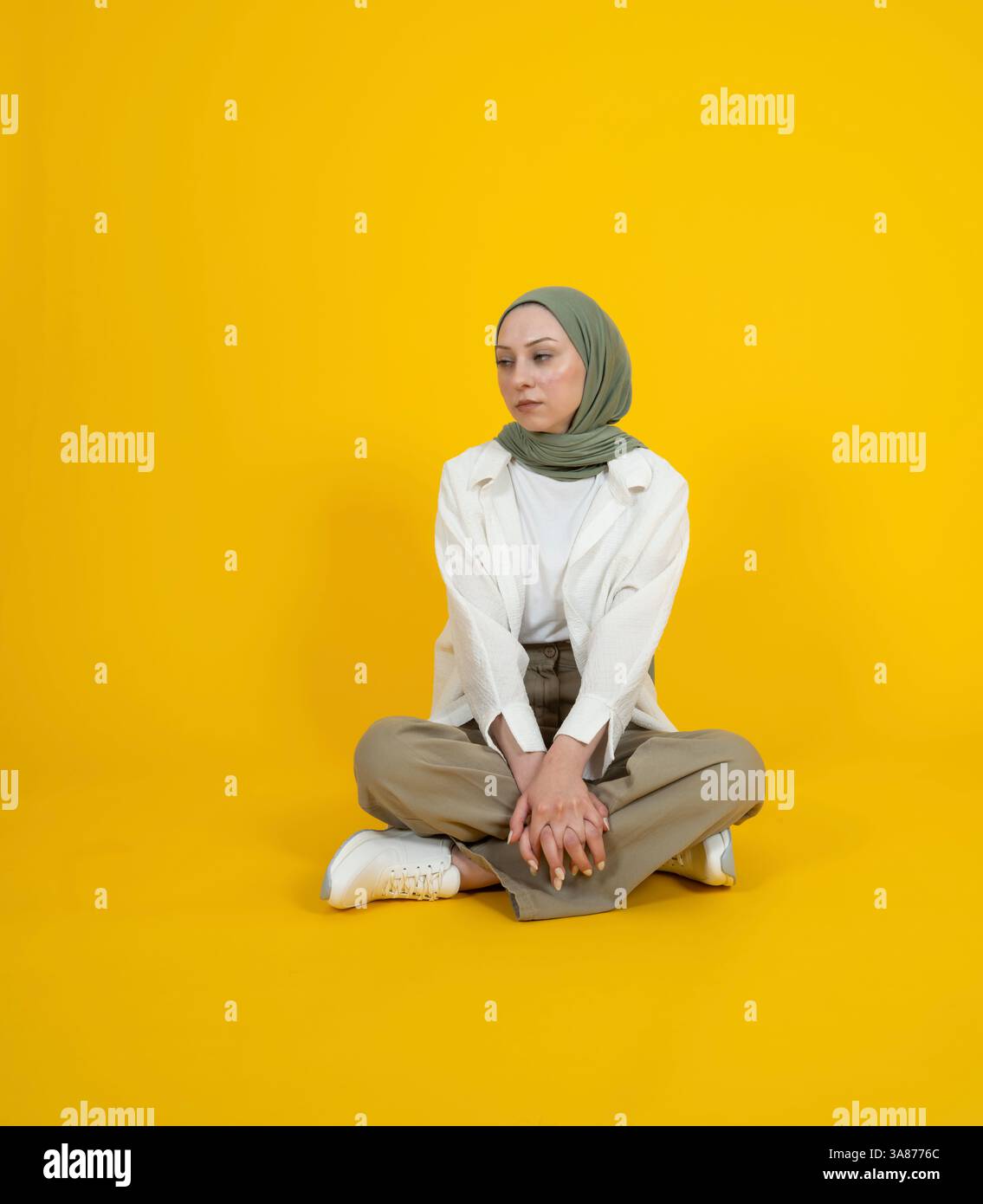 full body portrait of thoughtful sad woman. Muslim girl in hijab sit ...
