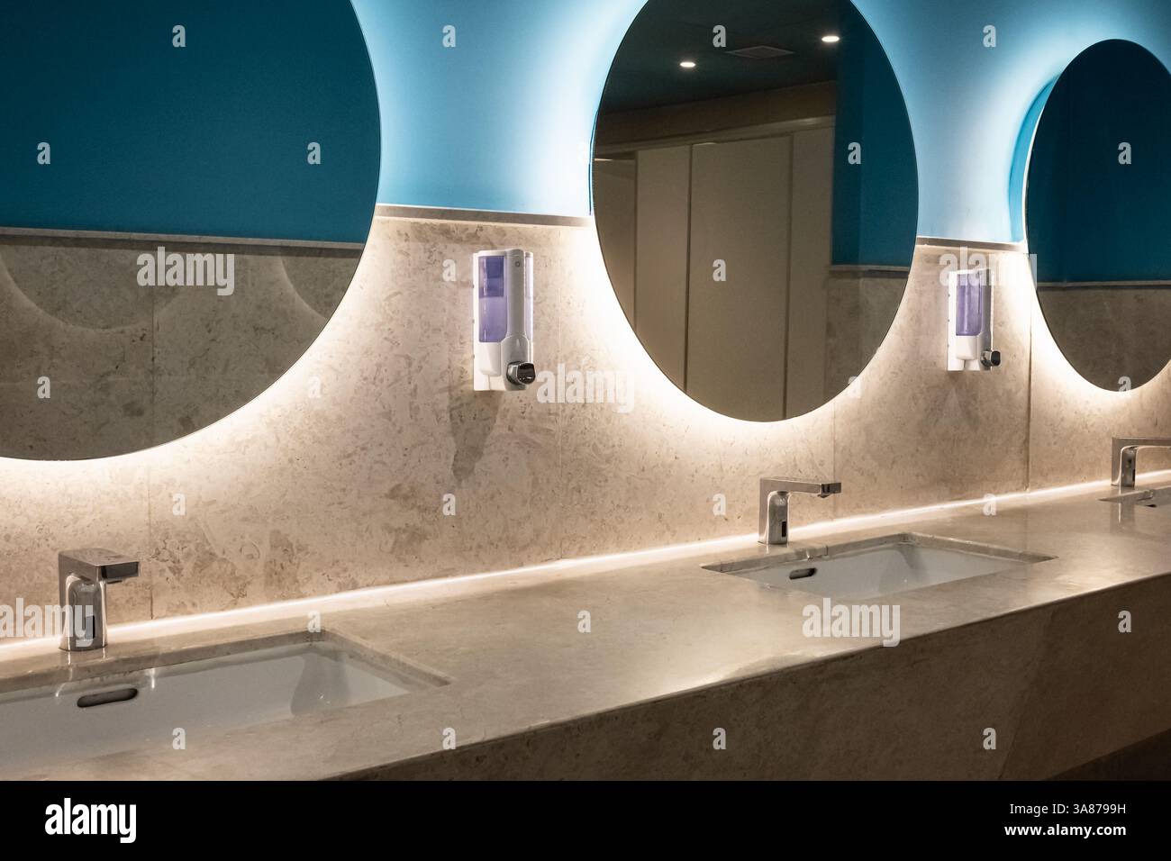 Modern toilet with a large round illuminated mirrors. Wide sink with ...
