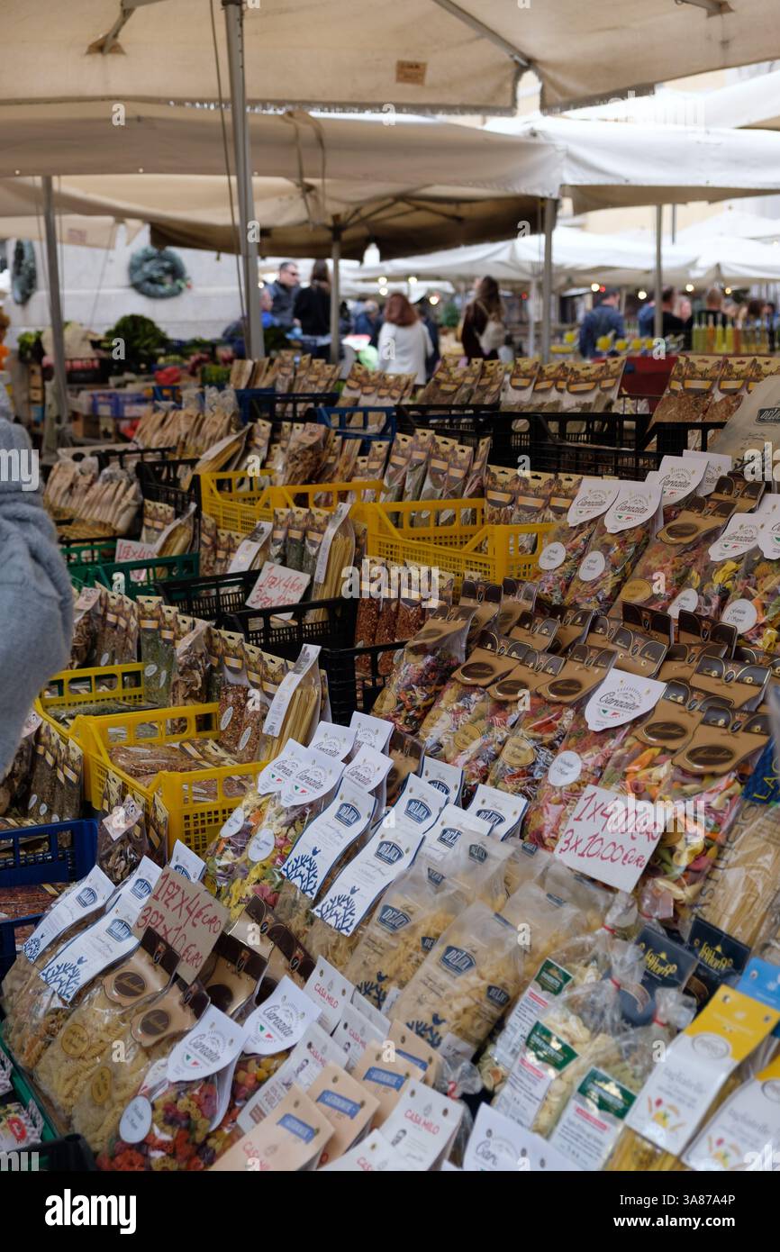 Shoppers browse a stall overflowing with various types of packaged ...