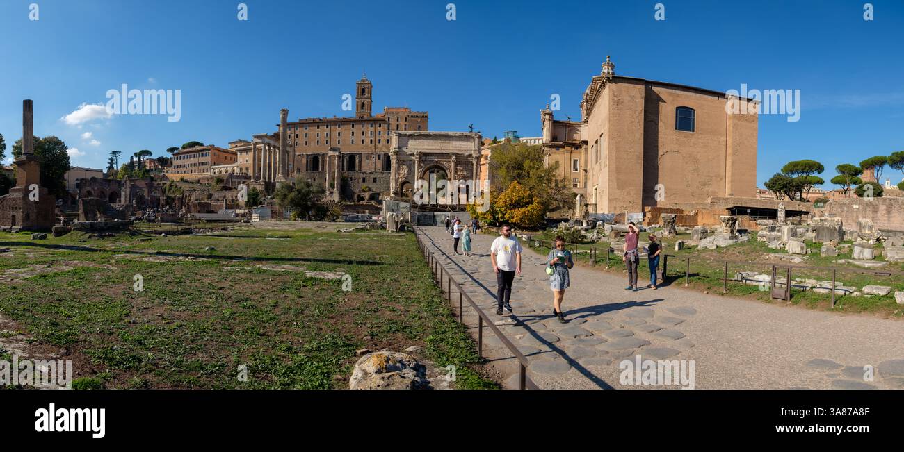 Tourists walk along a path exploring the ancient ruins of the Roman ...