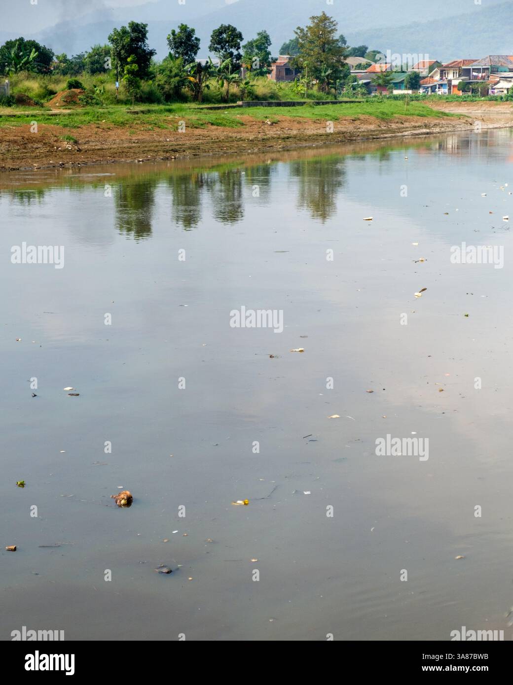 Garbage floats on the surface of a polluted river flowing past a ...