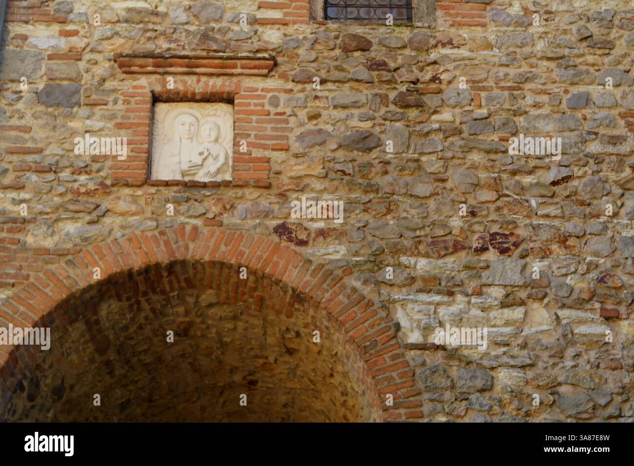 Bas-relief of Madonna with child embedded in a niche of a medieval wall ...