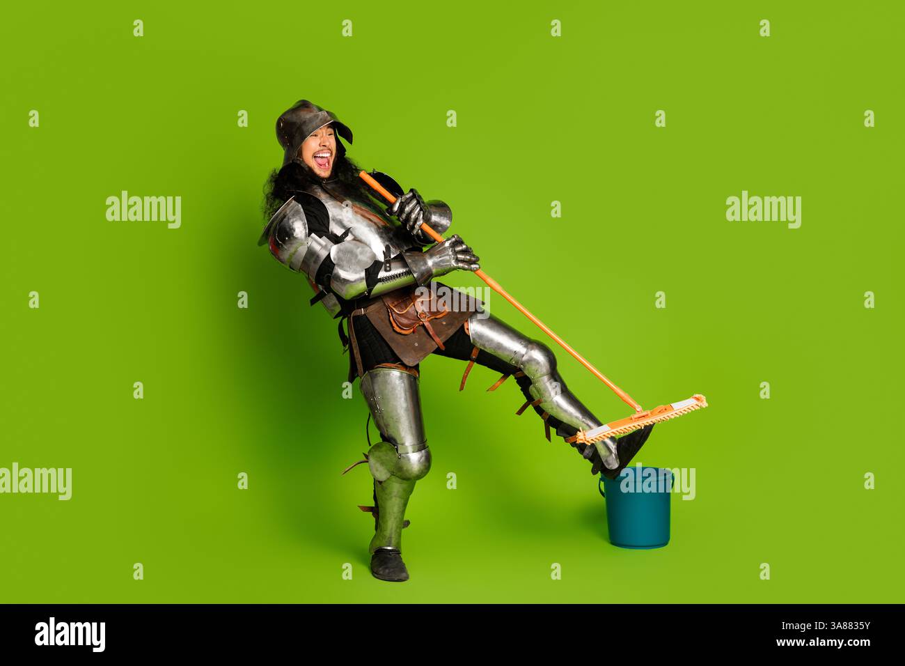 Funny medieval knight posing with a mop on a vibrant green background ...