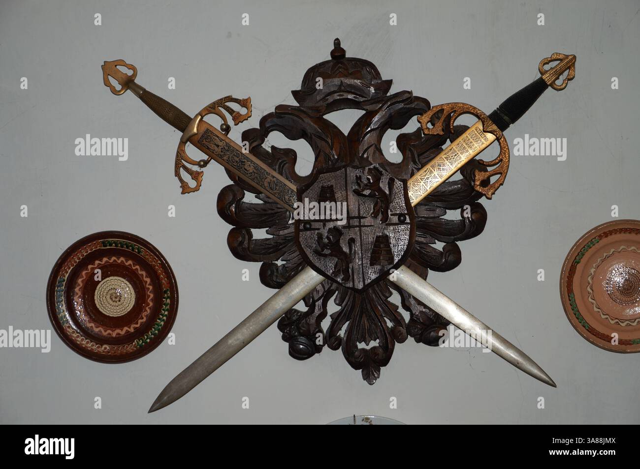 A vintage shield with two crossed swords displayed in an old rural ...