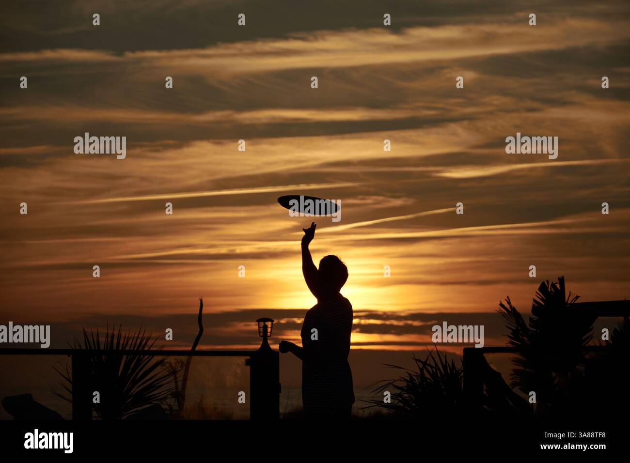 A waiter playfully balancing a tray during sunset at El Palmar, Spain ...