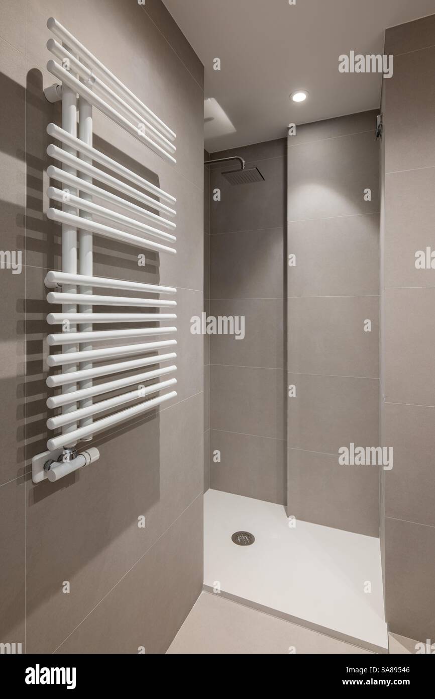 Modern shower with white towel radiator and minimalist tiled design ...
