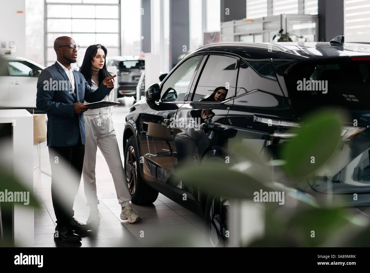 African-American dealer counseling a customer on buying a modern car at ...