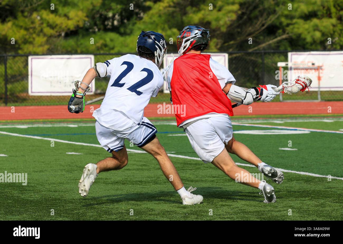 Two young athletes compete on a turf field during a lacrosse game Stock ...