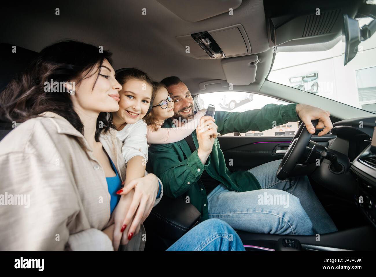 A happy young family in a modern car dealership after completing the ...
