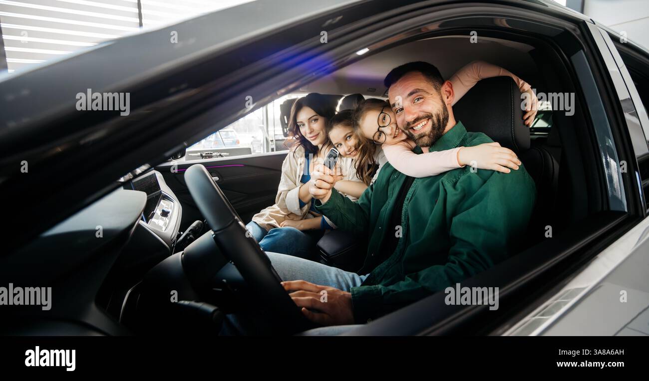 A happy young family in a modern car dealership after completing the ...