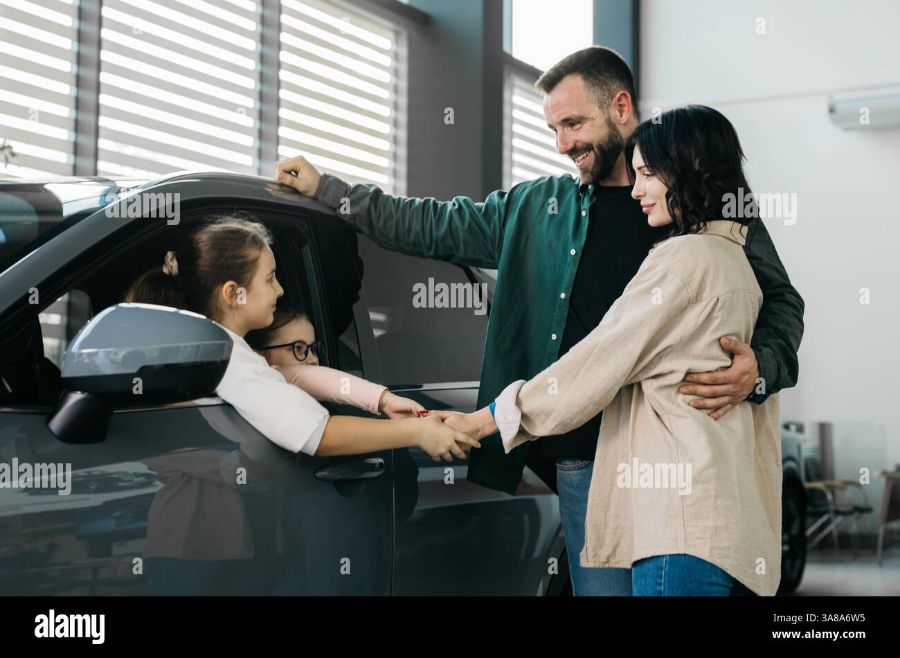 A happy young family in a modern car dealership after completing the ...
